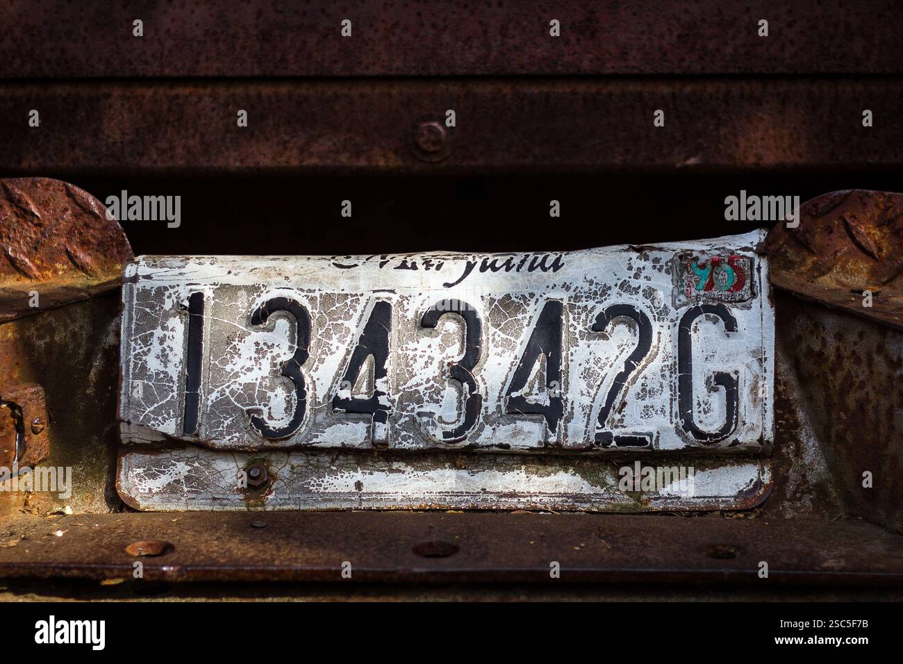 A weathered and rusted license plate, displaying the number 1343426, is ...