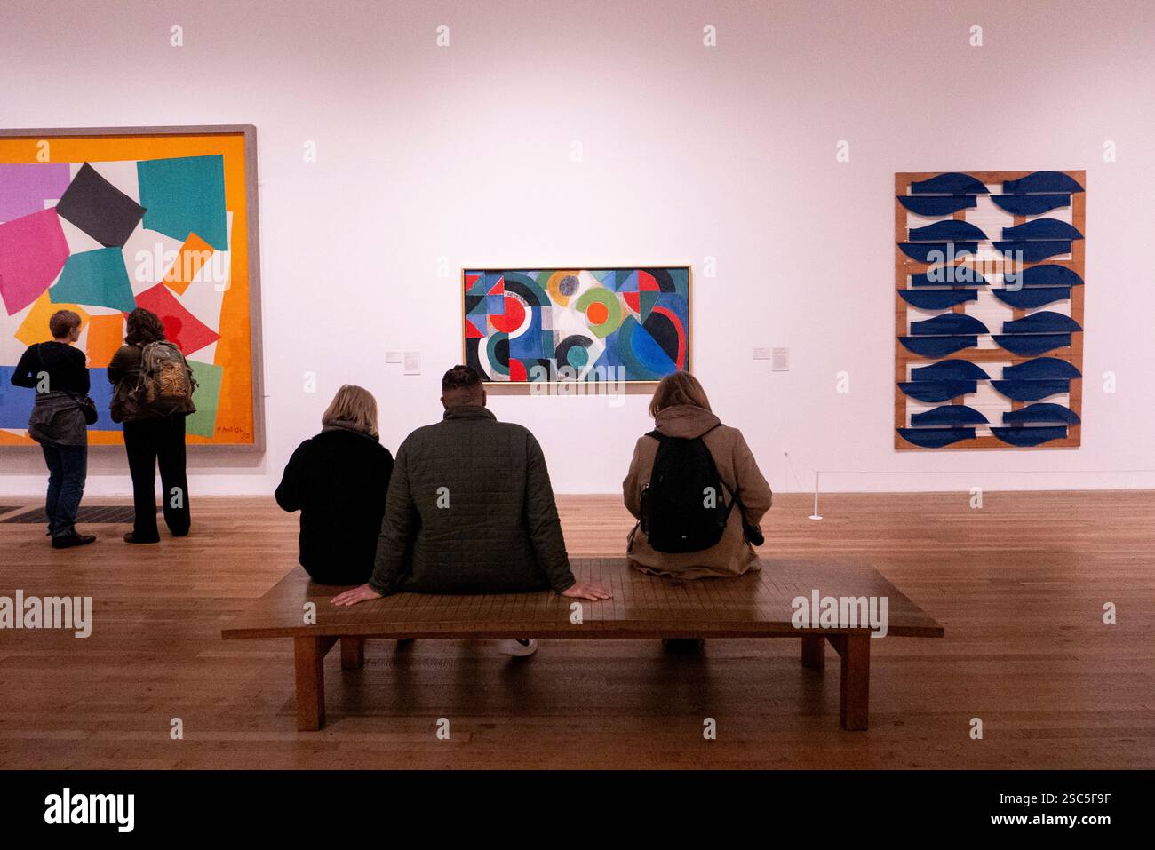 Poeple sit at The Tate Modern and look at Sonia Delaunay's artwork ...