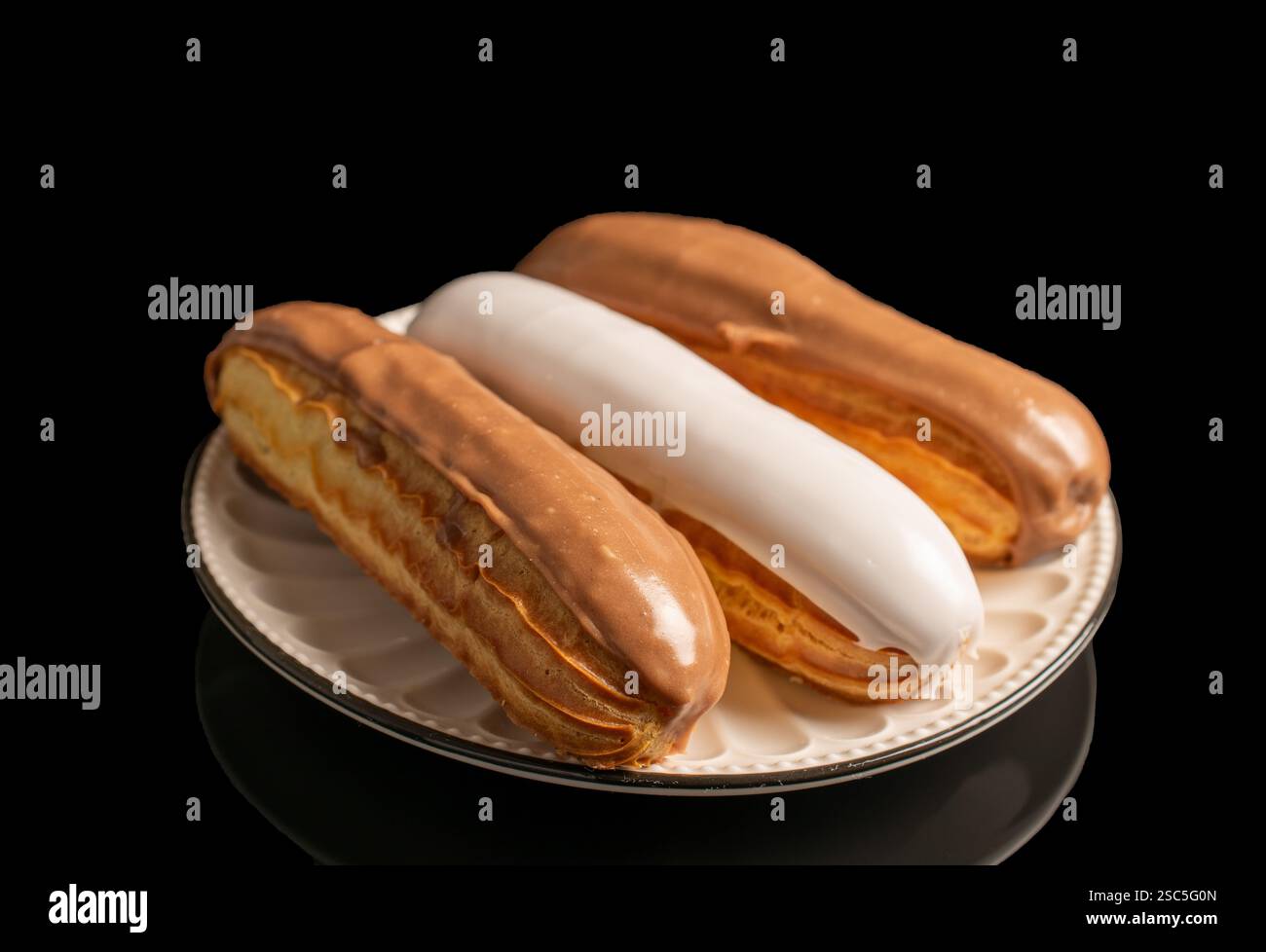 : Three eclairs with cream filling on a ceramic saucer, close-up ...