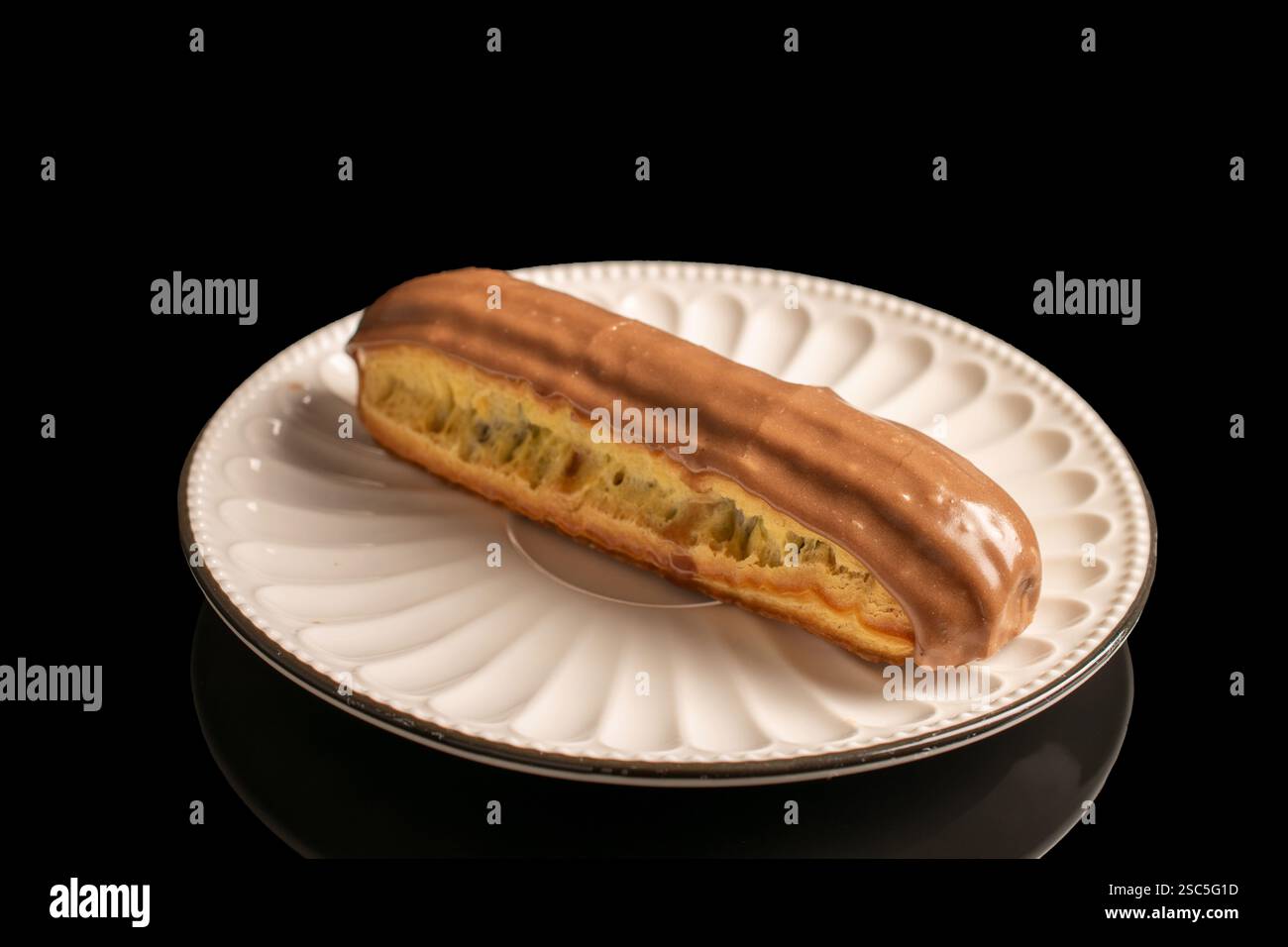 : One eclair with cream filling on a ceramic saucer, close-up, isolated ...