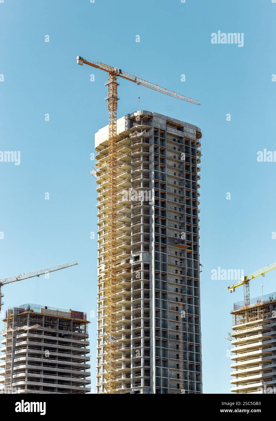Skyscraper under construction with a crane, high-rise concrete structure in an urban metropolis ...