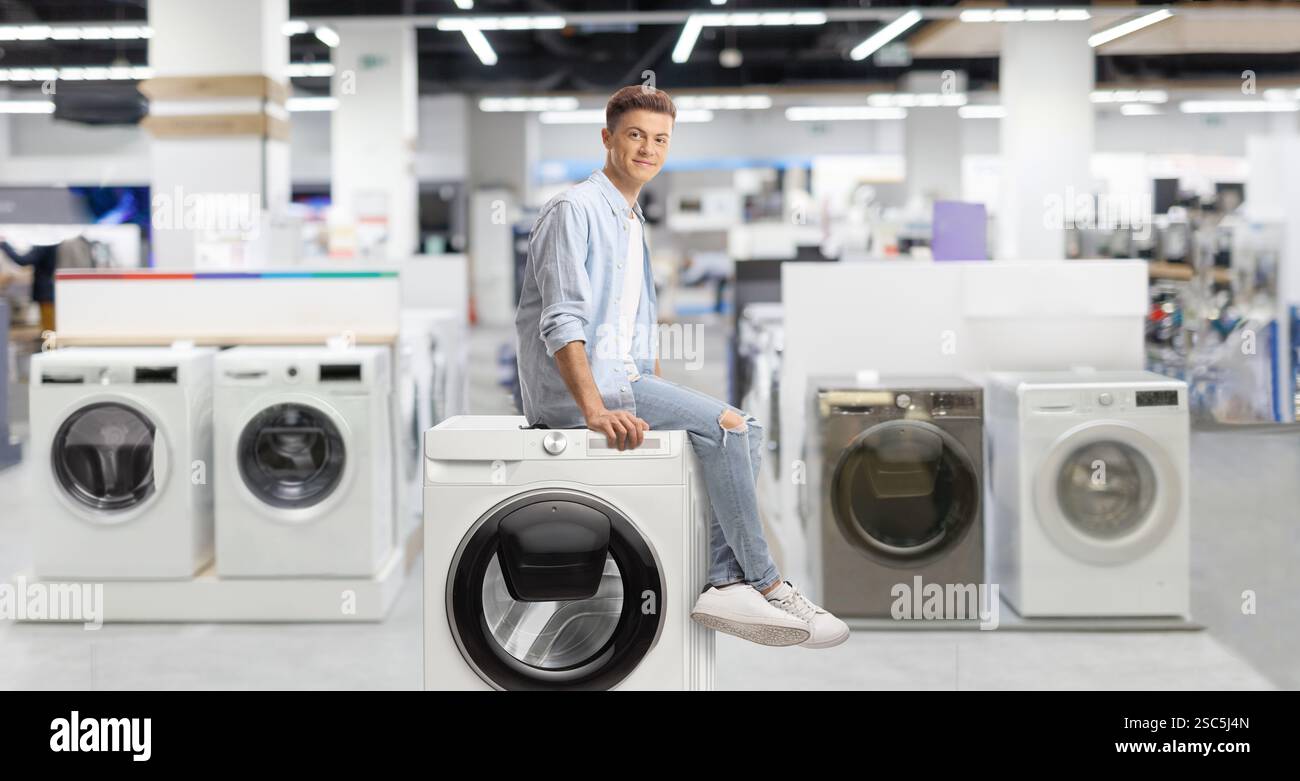 Young guy sitting on top of a washing machine at a store Stock Photo ...