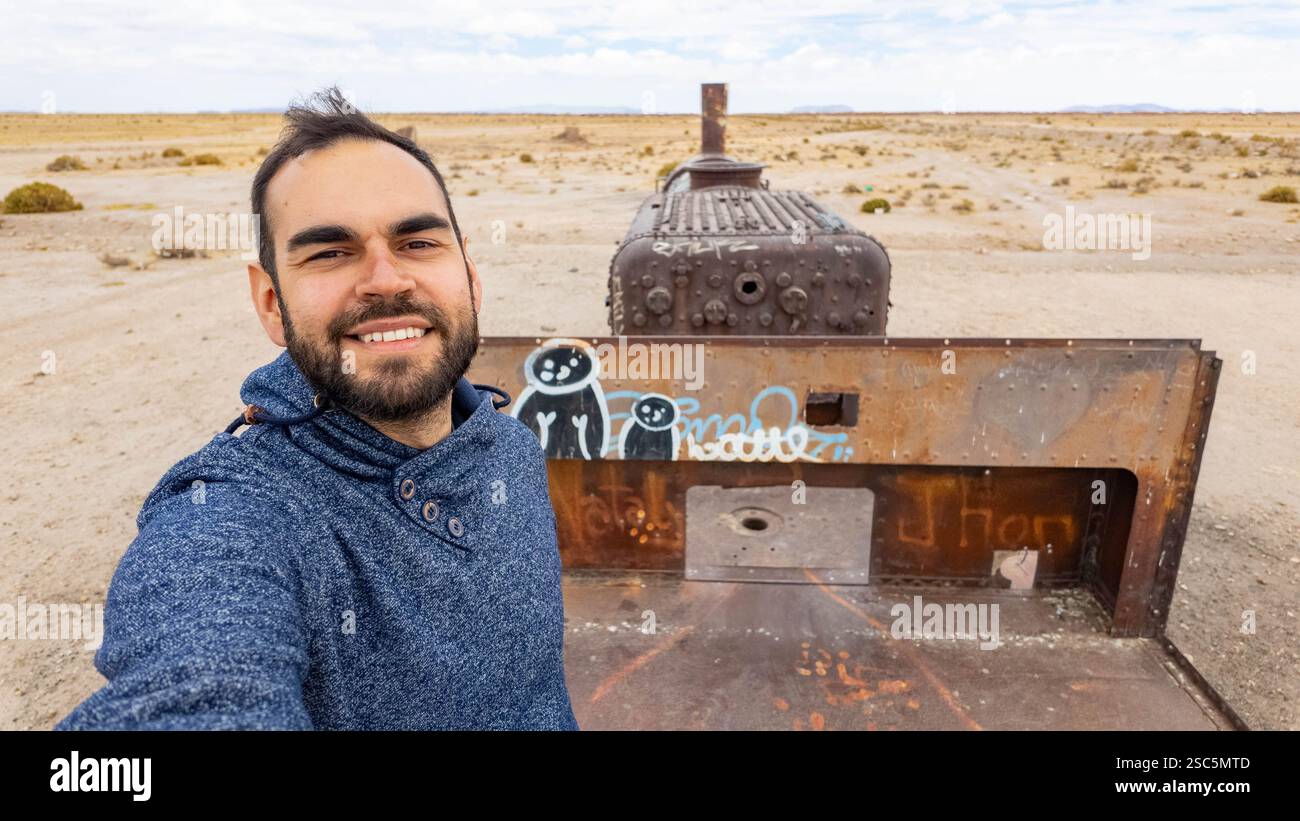 Traveler man taking a selfie over an old rusty locomotive in Uyuni's ...