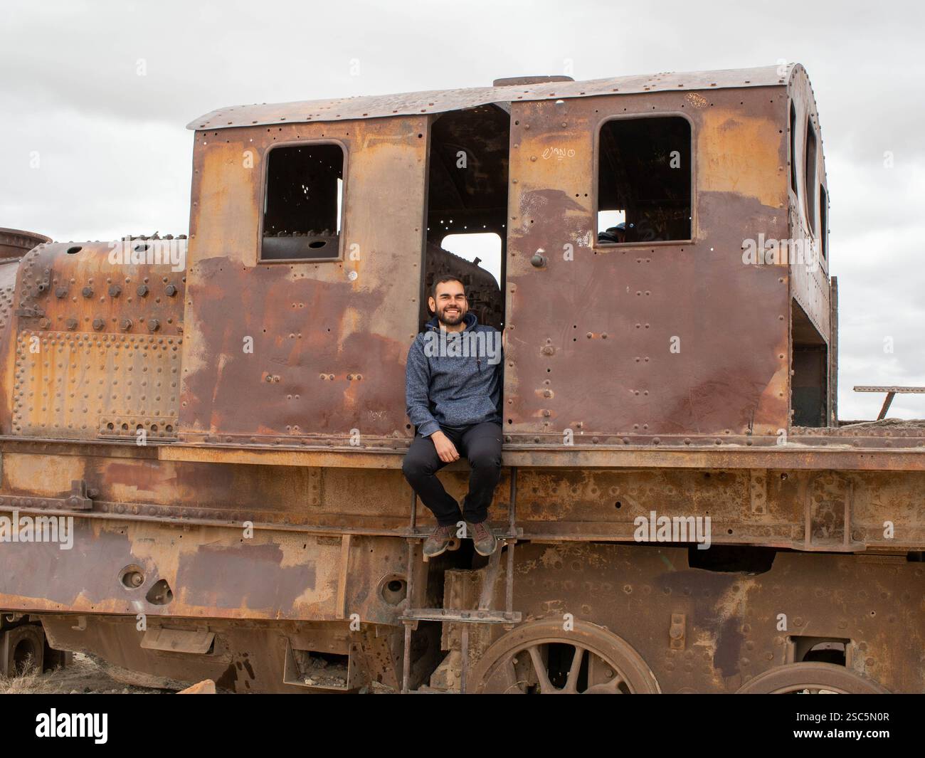 Traveler man posing in an old rusty locomotive in Uyuni's train ...