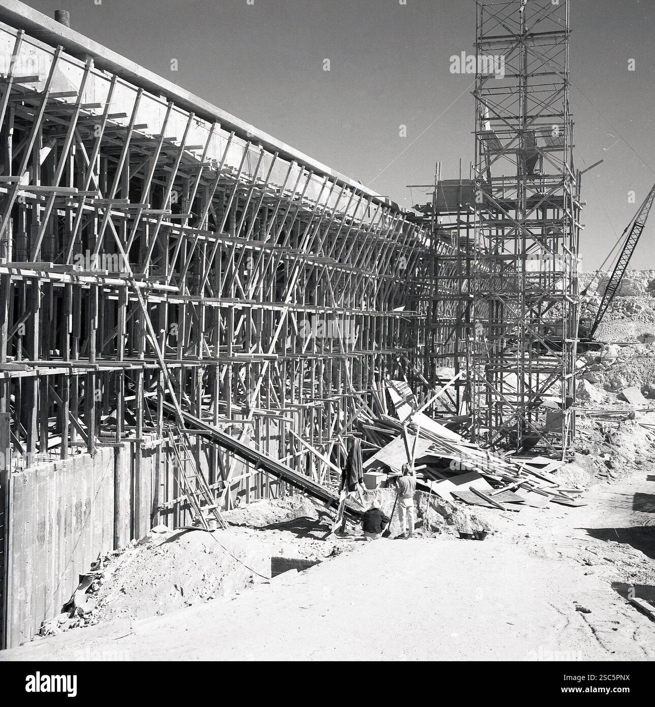 1960s, historical, out in the desert, a large construction site ...