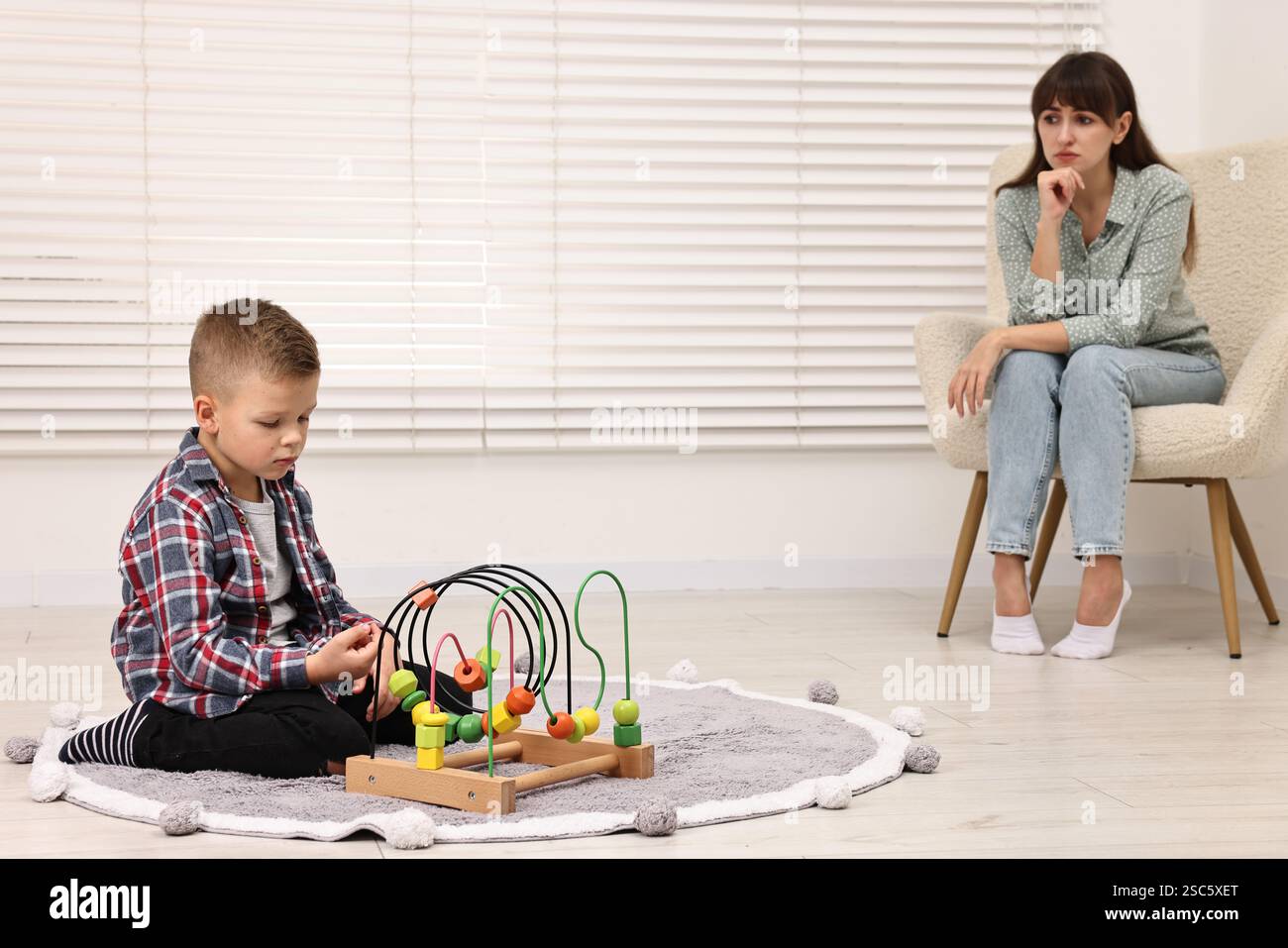 Psychologist observing little boy playing in autism treatment center ...