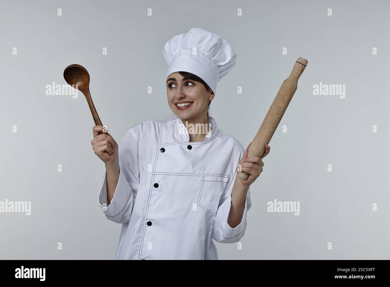 Professional chef with rolling pin and ladle on light grey background ...