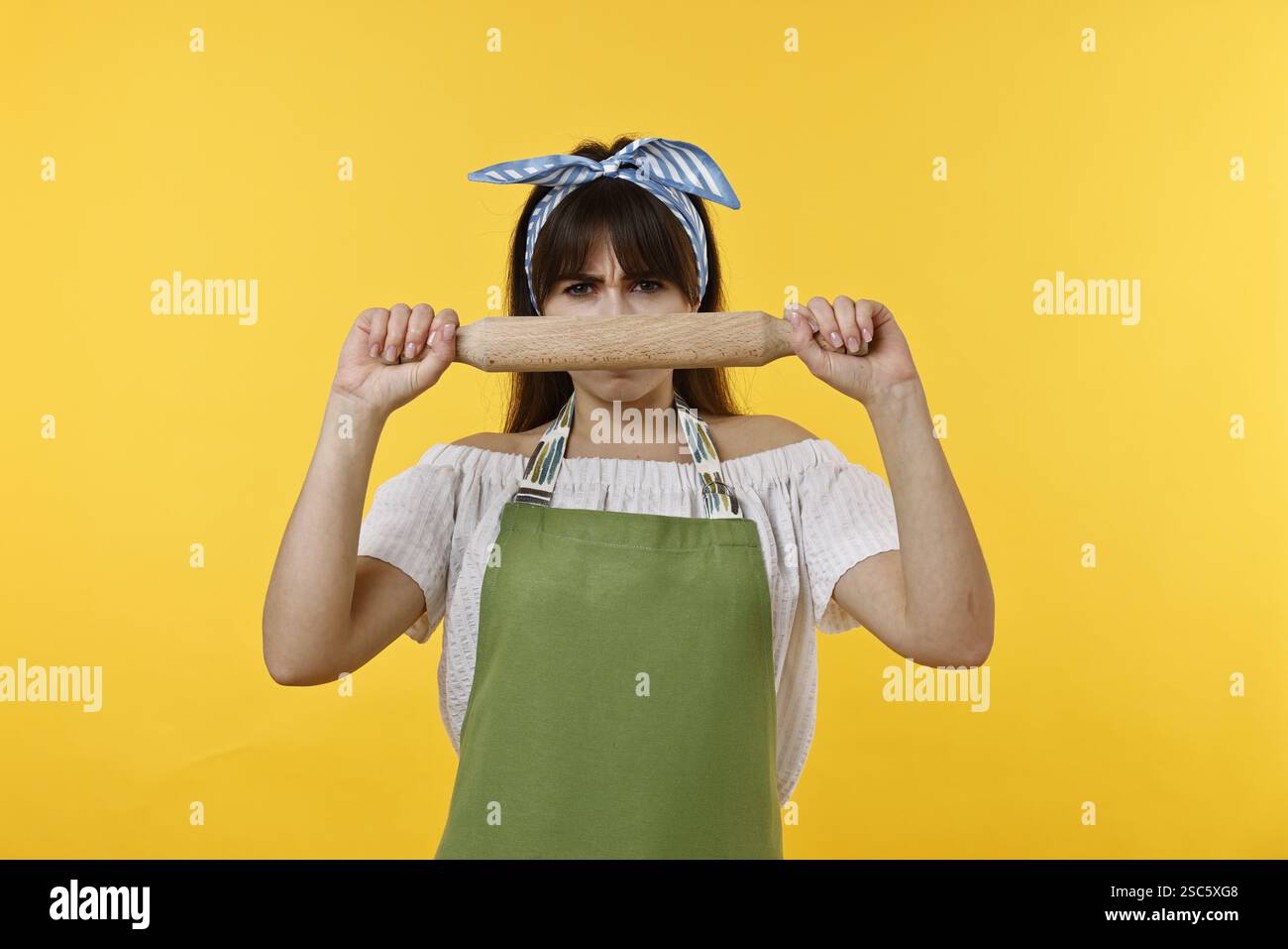Angry woman with rolling pin on yellow background Stock Photo - Alamy