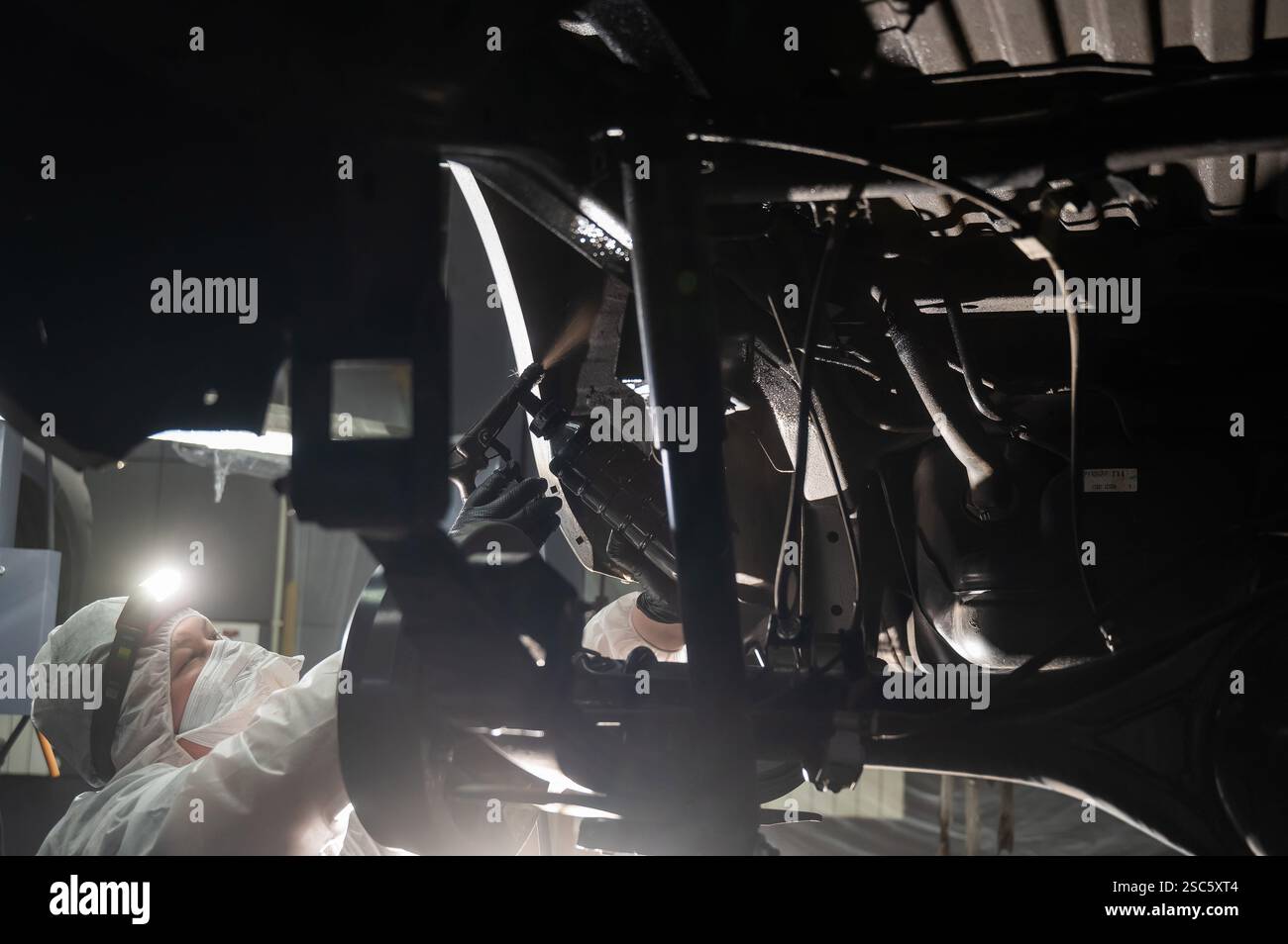An auto mechanic applies anti-corrosion mastic to the underbody of a ...