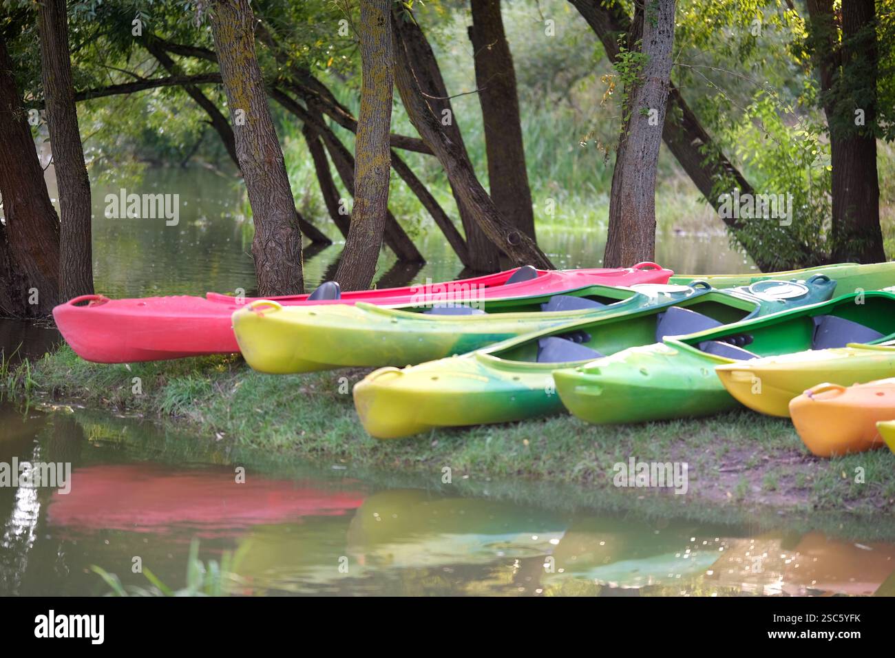 Many canoes of different colors on the river bank before training ...