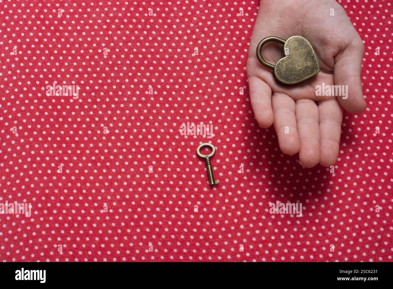 Hand holding a heart shaped lock and key on a red background Stock ...