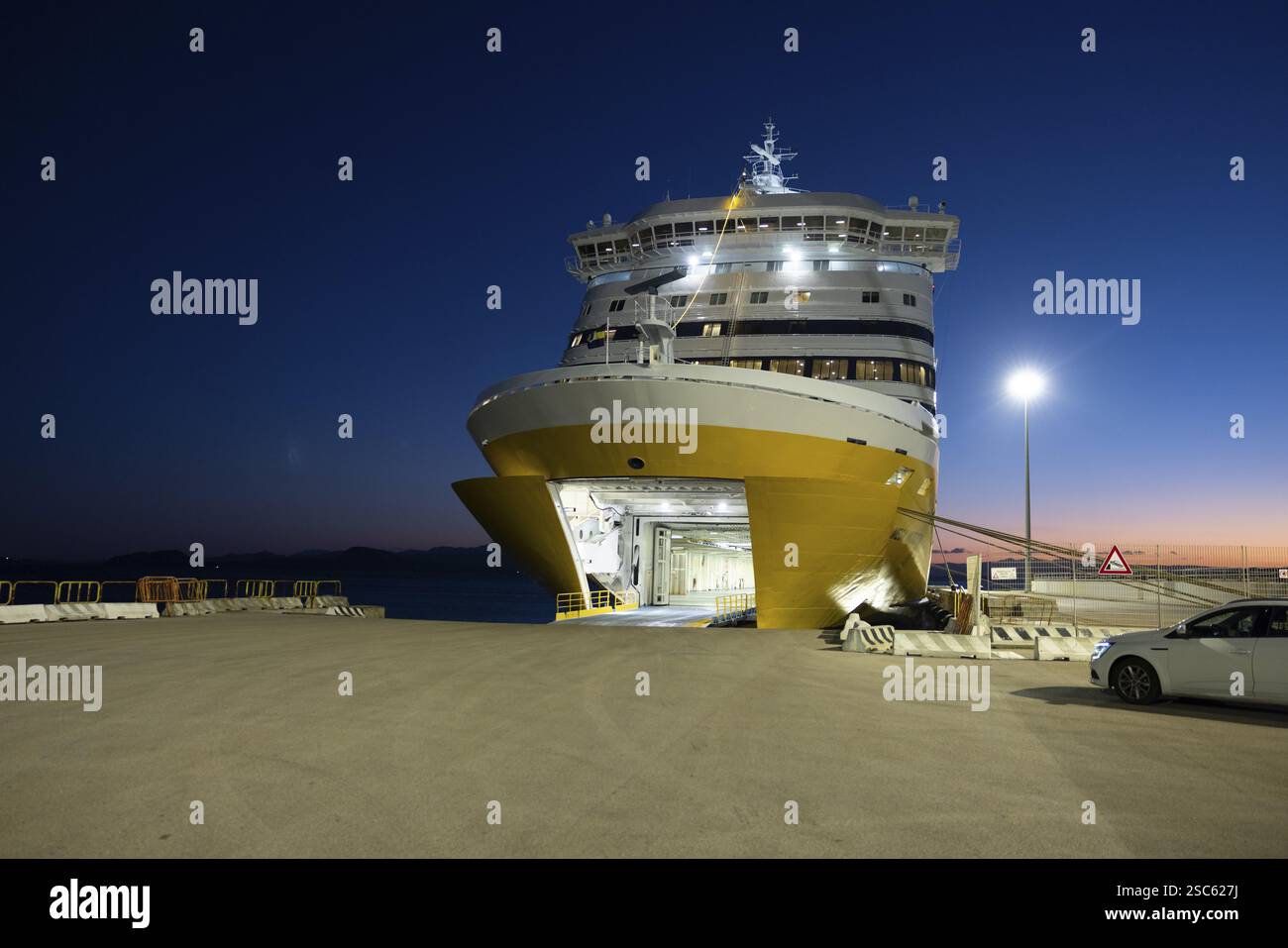 Car ferry with open bow gate hatch anchored in the harbour at sunset ...