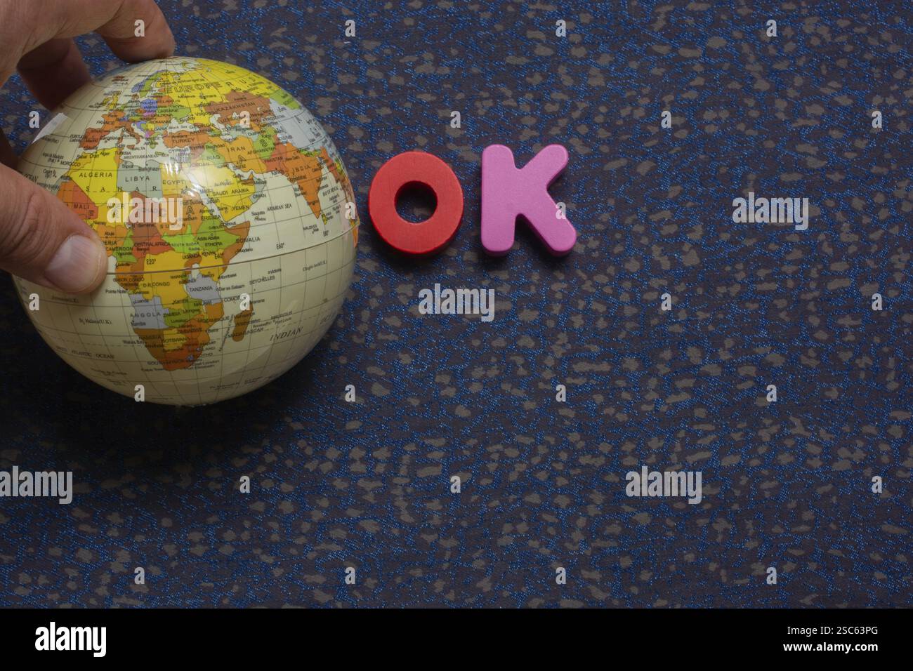 Hand holding globe model beside word OK Stock Photo - Alamy