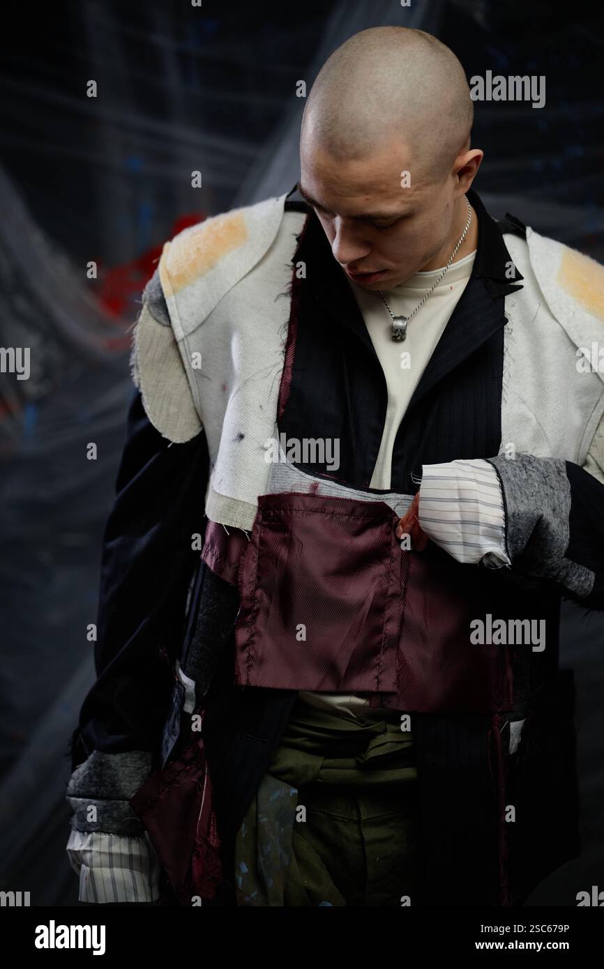 Vertical shot of male model with buzz cut wearing patchwork jacket with ...