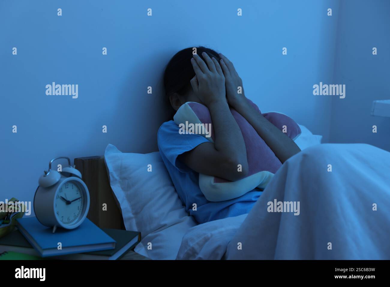 Afraid girl covering face with hands in bed at night Stock Photo - Alamy