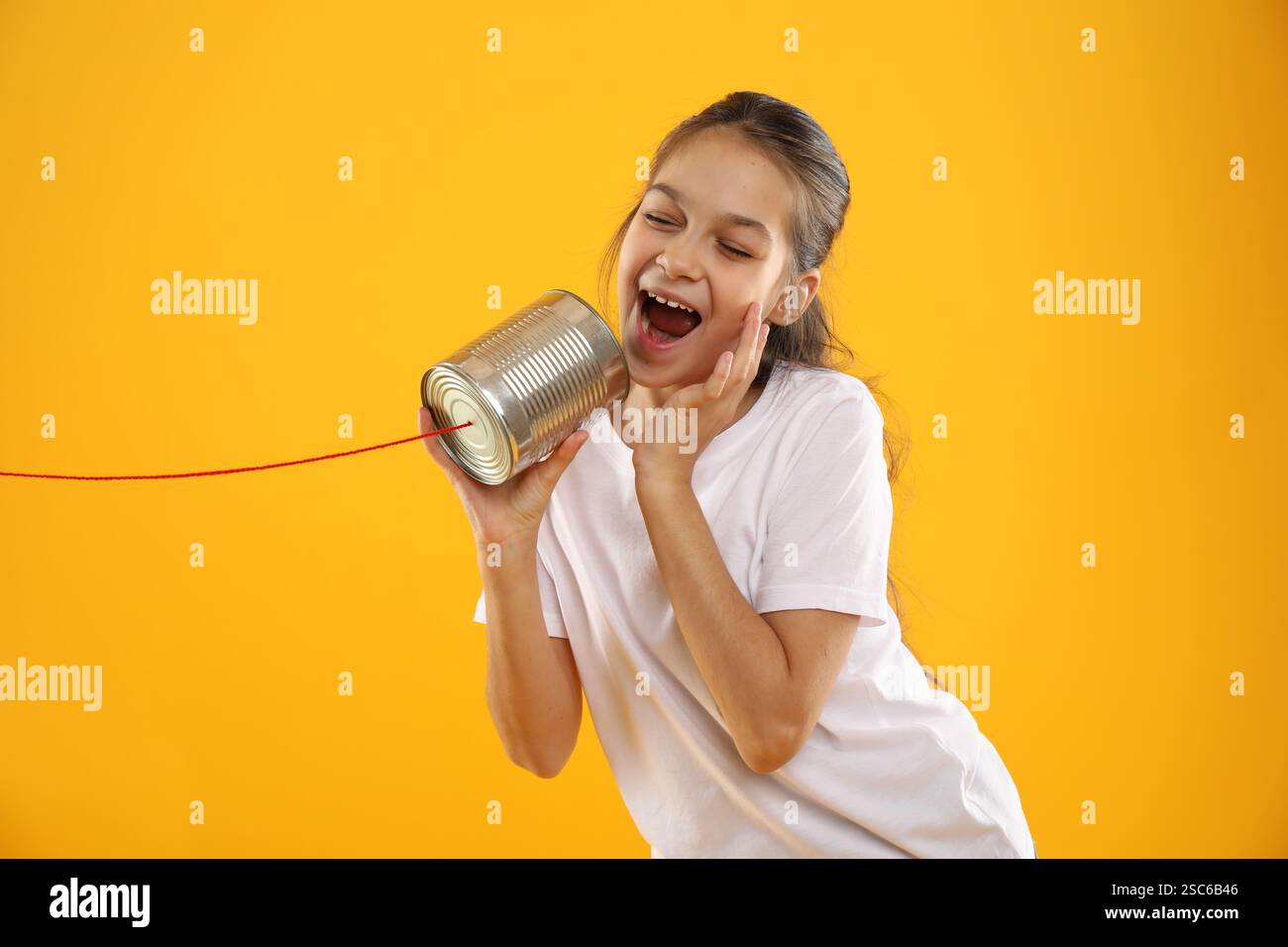 Girl using tin can telephone on yellow background Stock Photo - Alamy