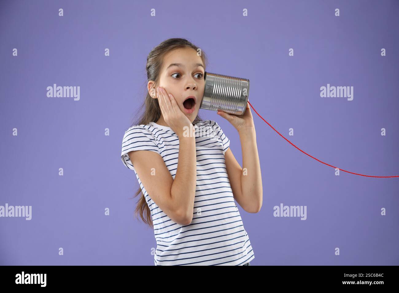 Girl using tin can telephone on violet background Stock Photo - Alamy