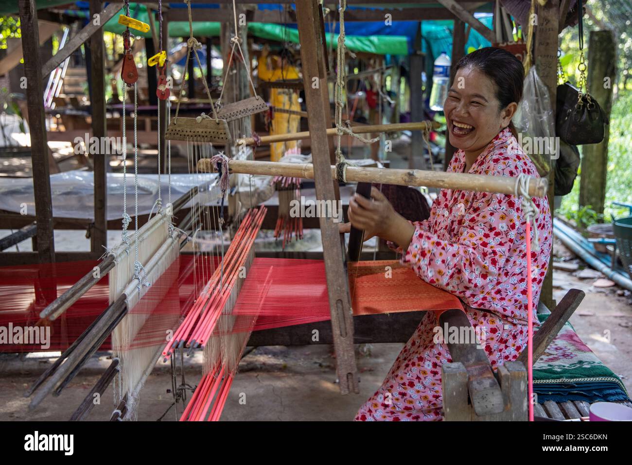 Laughing woman making silk fabric on a loom in a handicraft factory on ...