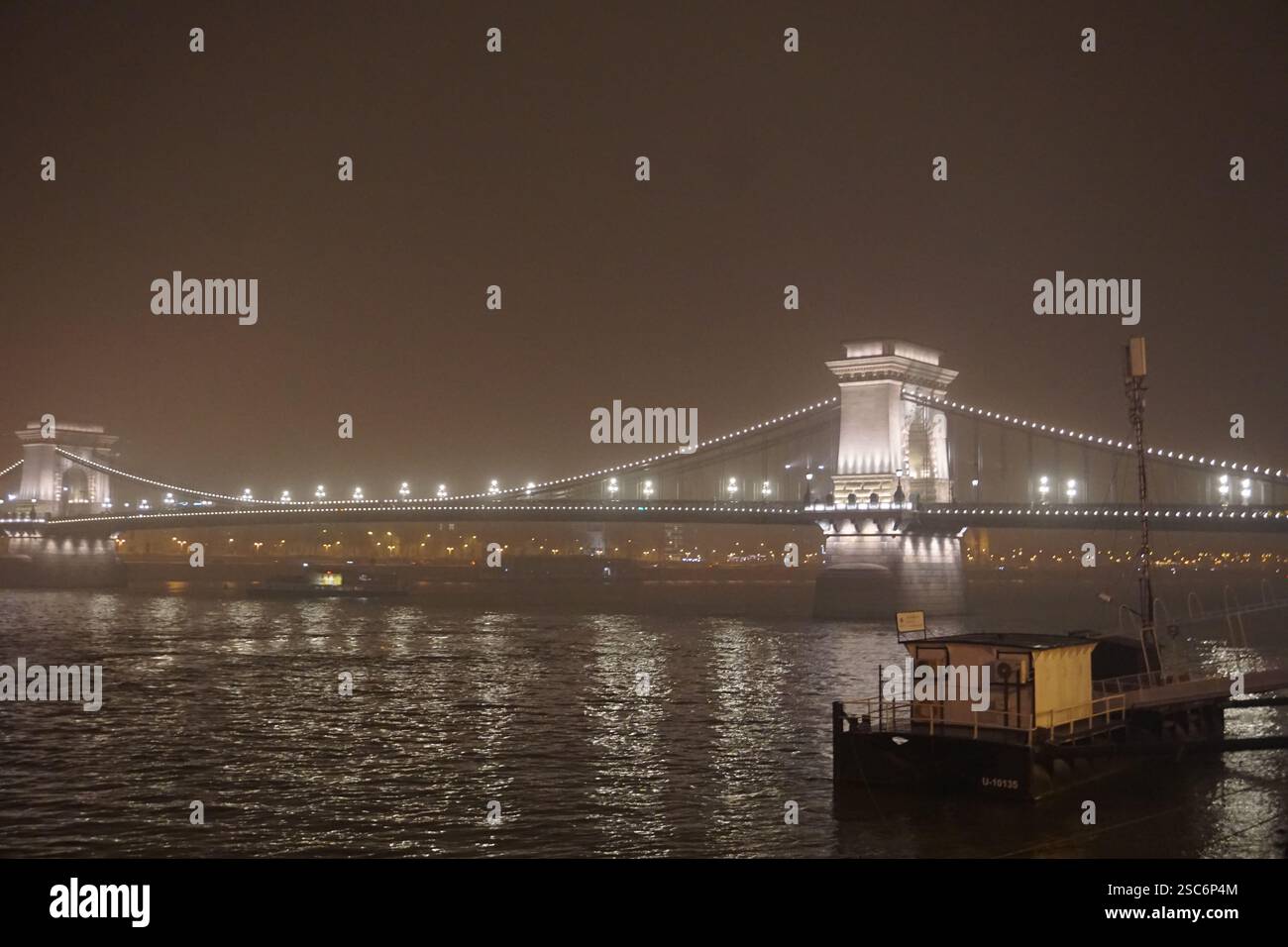 A steam boat on river Donau crosses the illuminated Széchenyi Chain ...