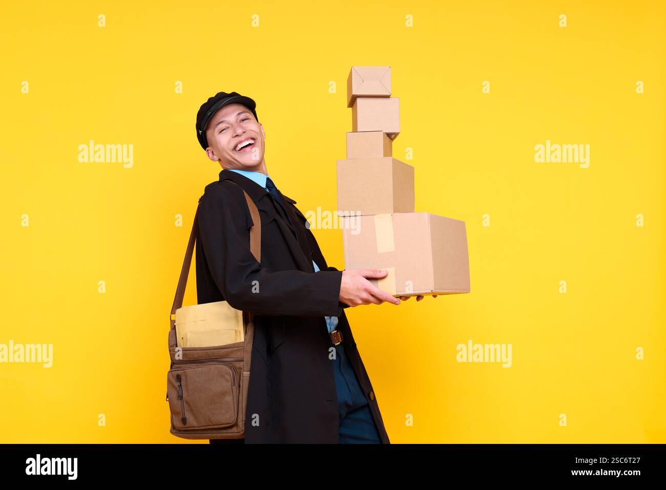 Happy postman with bag and parcels on yellow background Stock Photo - Alamy