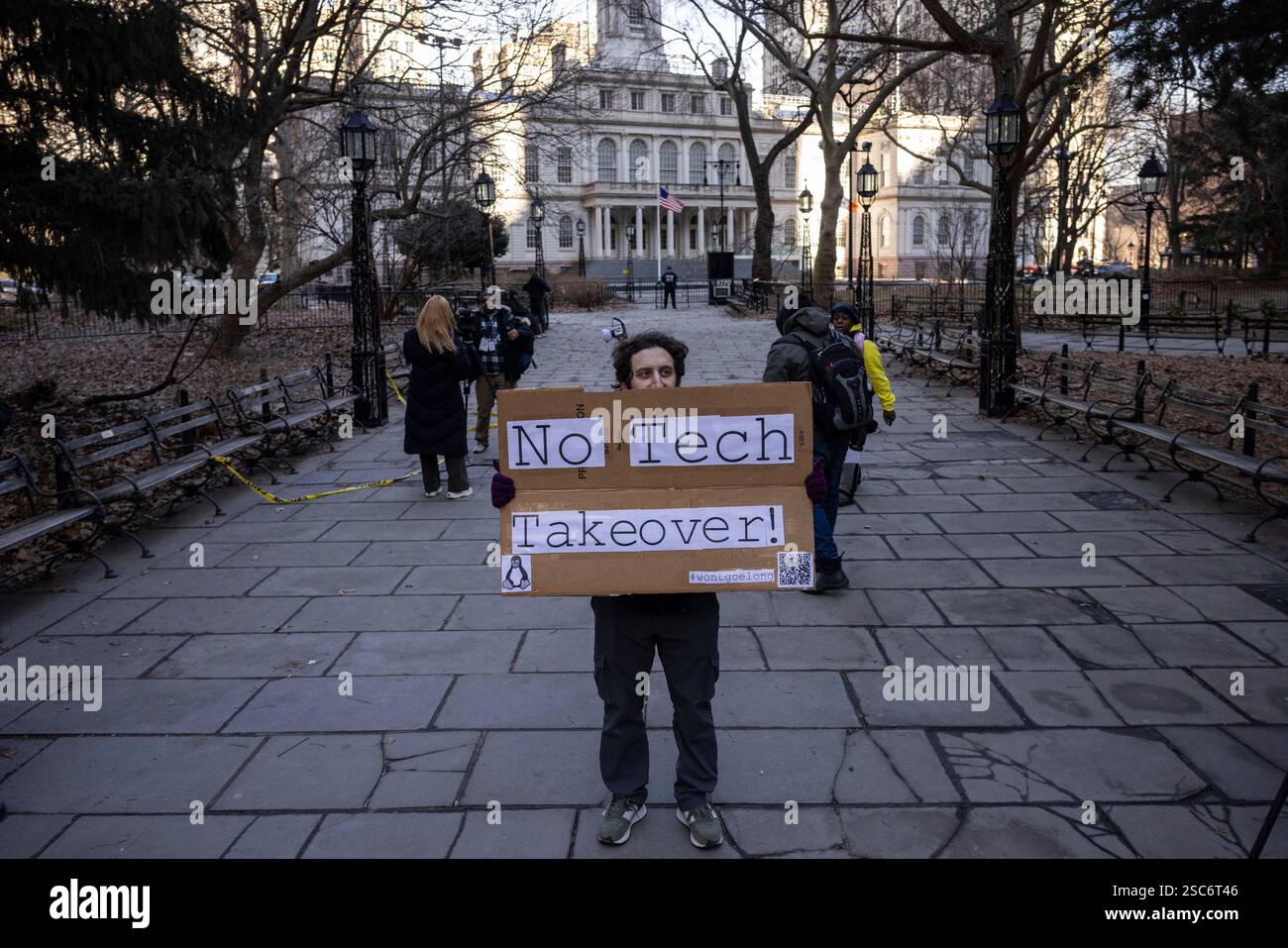 A person holds a sign reading "No Tech Takeover" during a protest ...