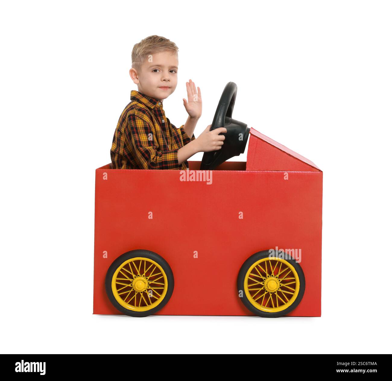 Little boy waving while driving car made of cardboard on white ...