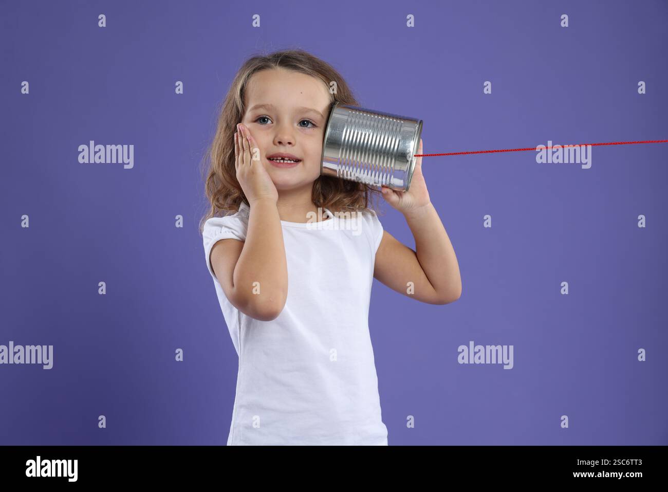 Girl using tin can telephone on violet background Stock Photo - Alamy