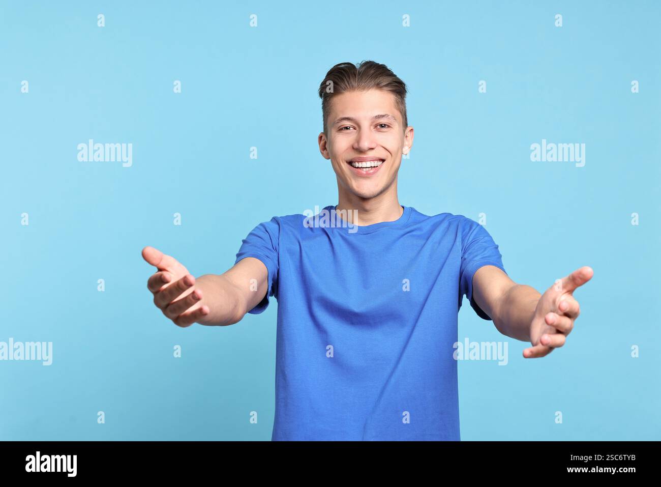Happy man welcoming friends or guests on light blue background Stock ...