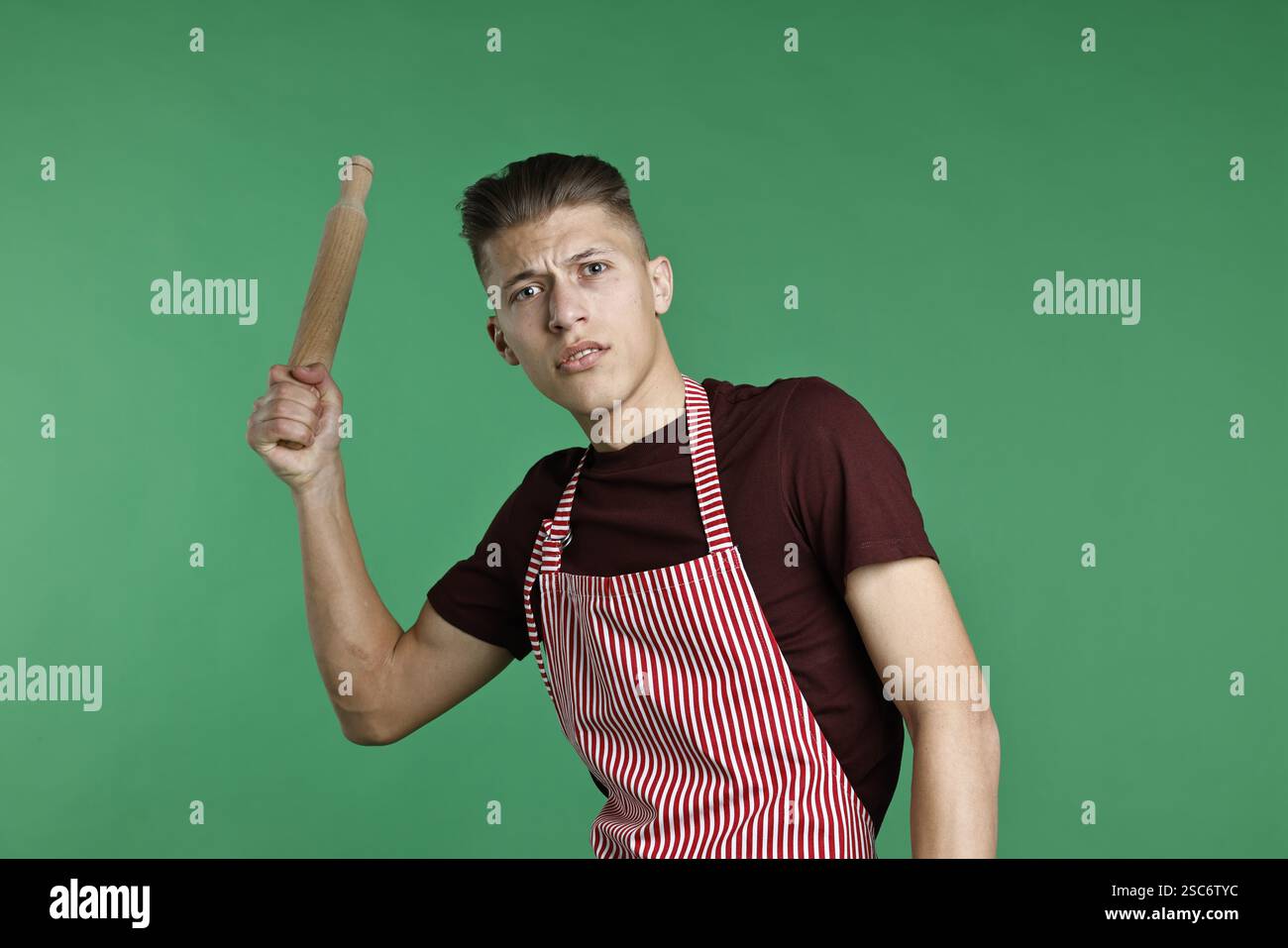 Angry man with rolling pin on green background Stock Photo - Alamy