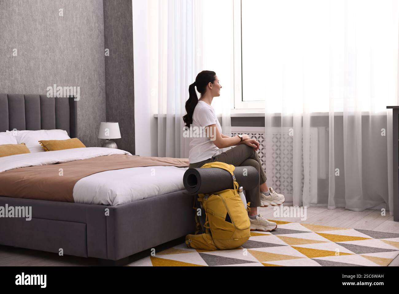 Traveller with backpack sitting on bed in hotel room Stock Photo - Alamy