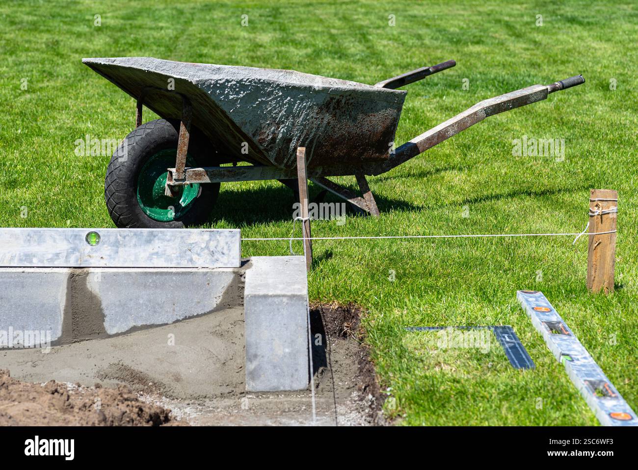 A wheelbarrow filled with liquid concrete mixed by hand in a ...