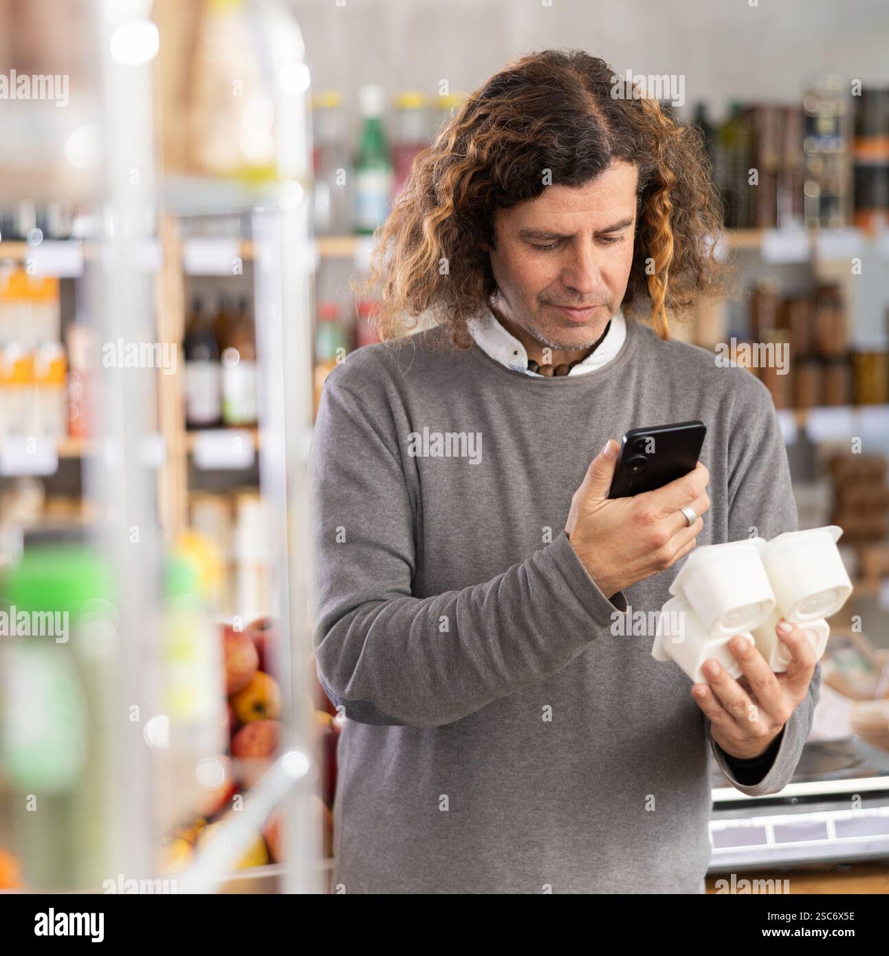 Checking expiration date of yogurt - male shopper scans QR code on label of yogurt using ...