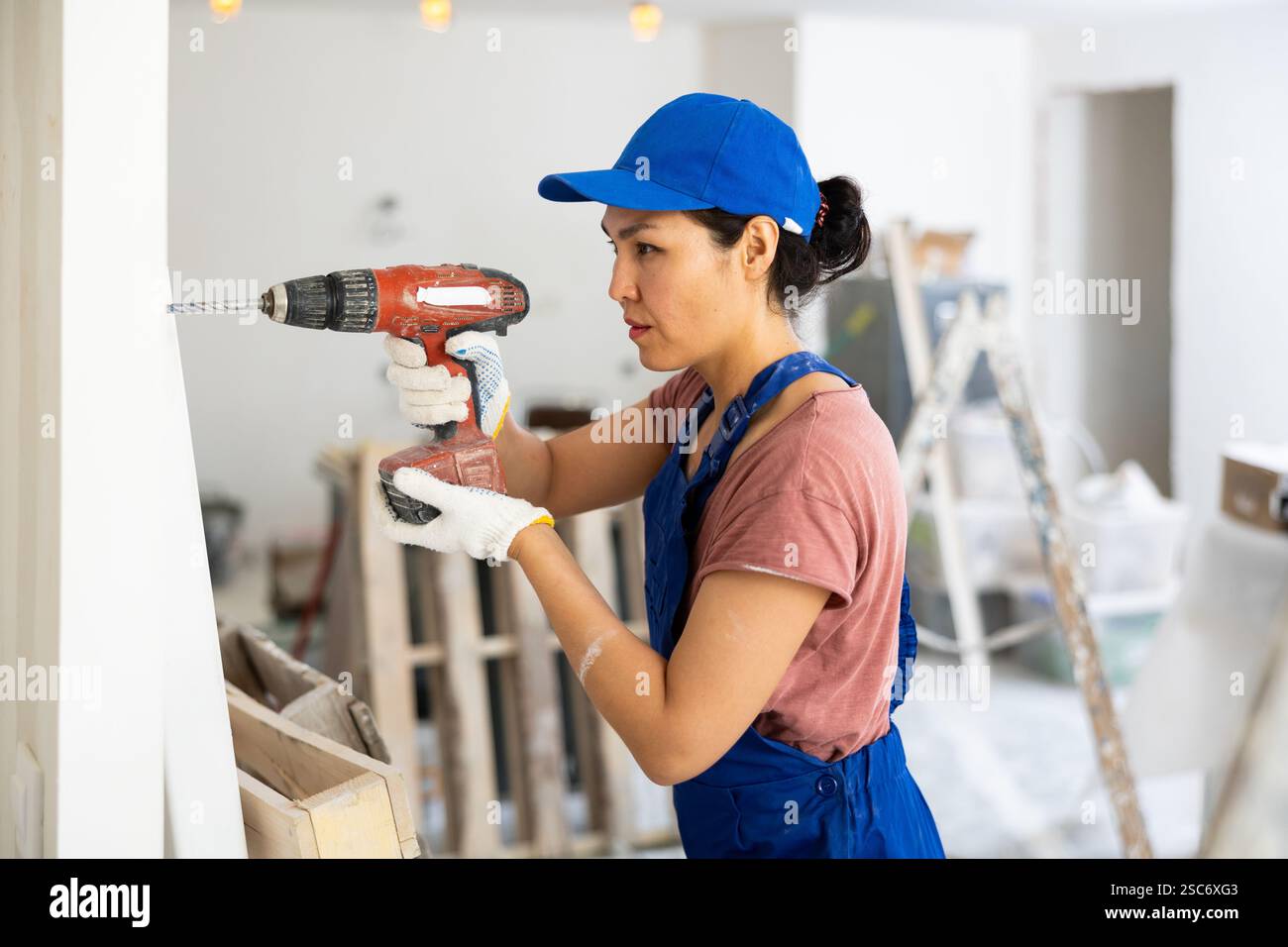 Woman builder using drill to bore hole in wall Stock Photo - Alamy