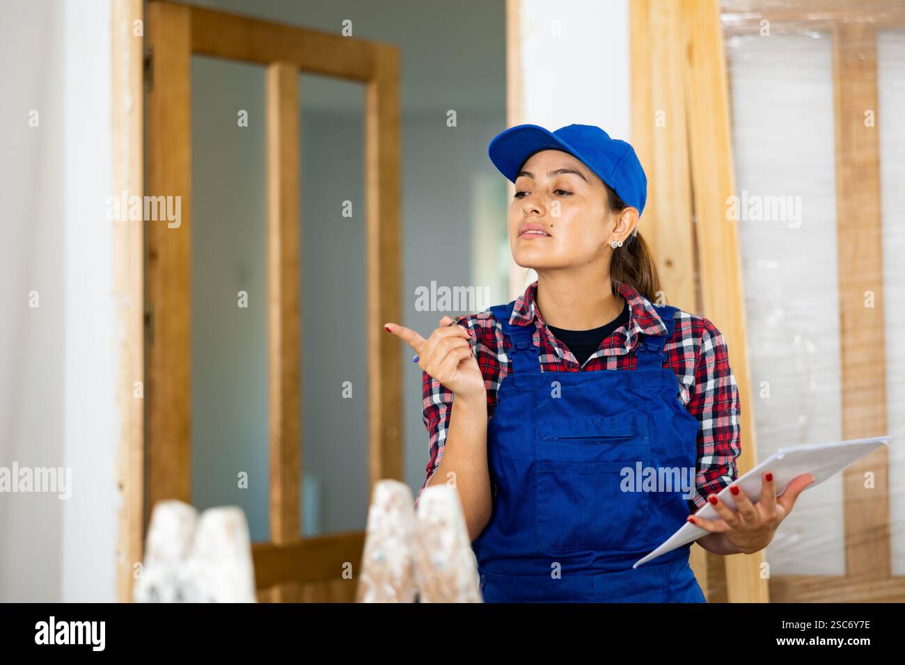 Female construction worker checking documents in apartment Stock Photo ...