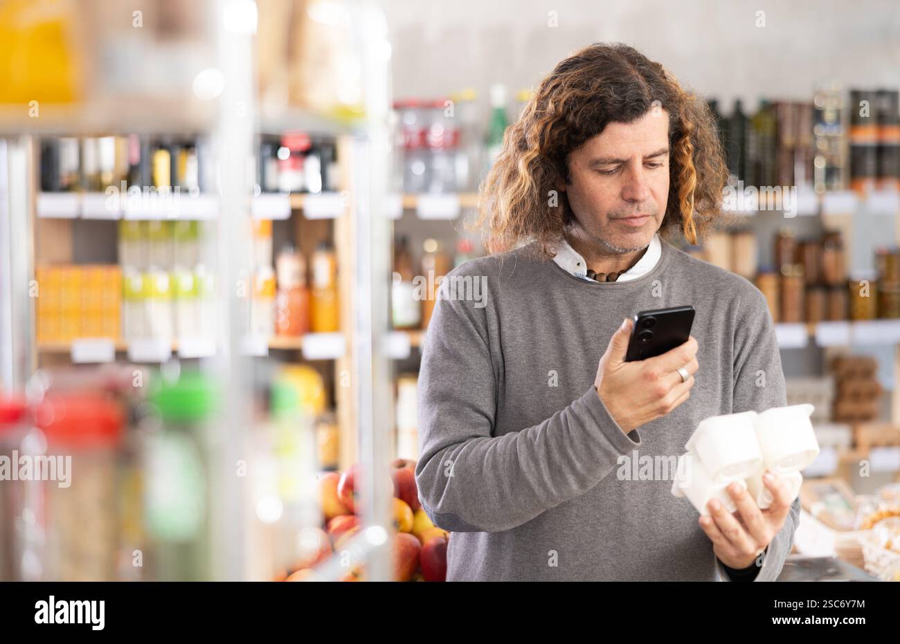 Checking expiration date of yogurt - male shopper scans QR code on ...