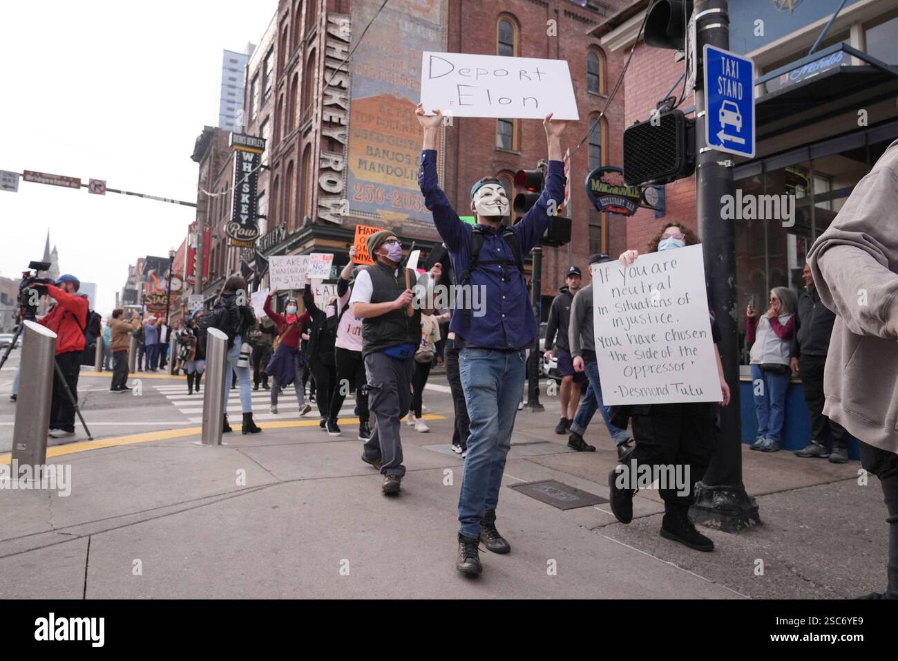 Protesters hold up signs while demonstrating, Wednesday, Feb. 5, 2025 ...