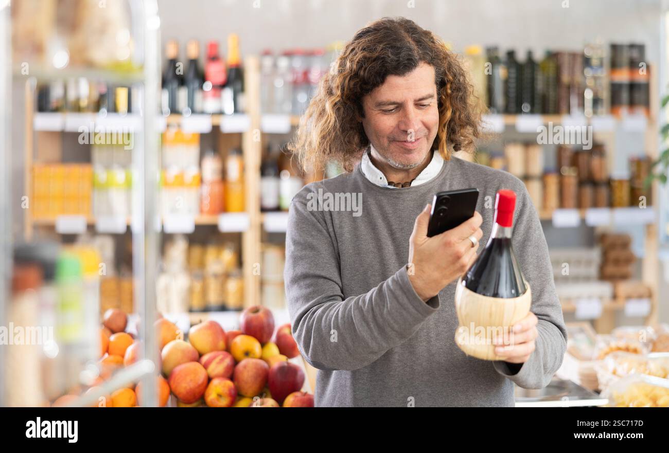 Male shopper scanning QR code on bottle wine label in grocery ...