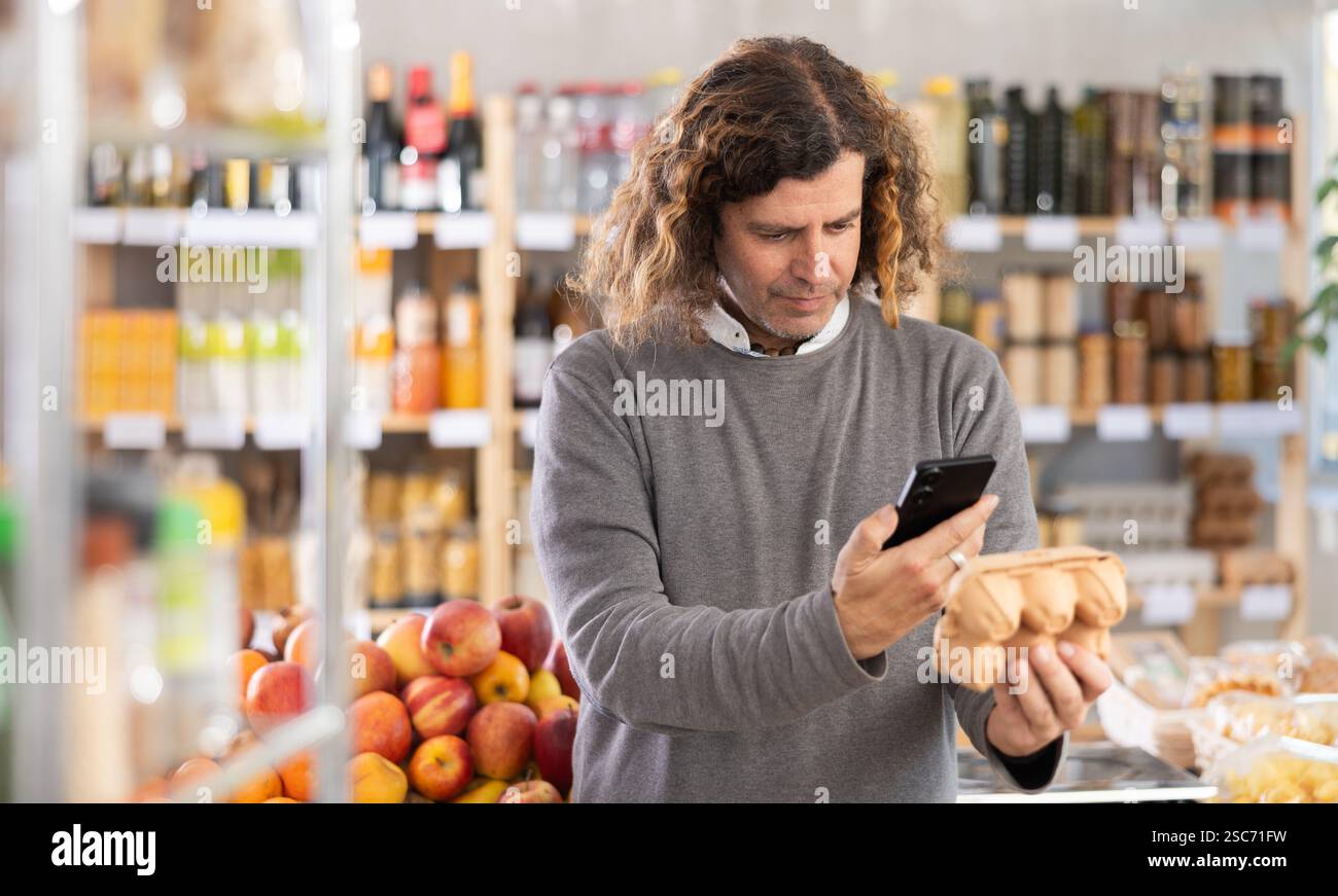Male buyer scans QR code on packaging of chicken eggs label in grocery ...