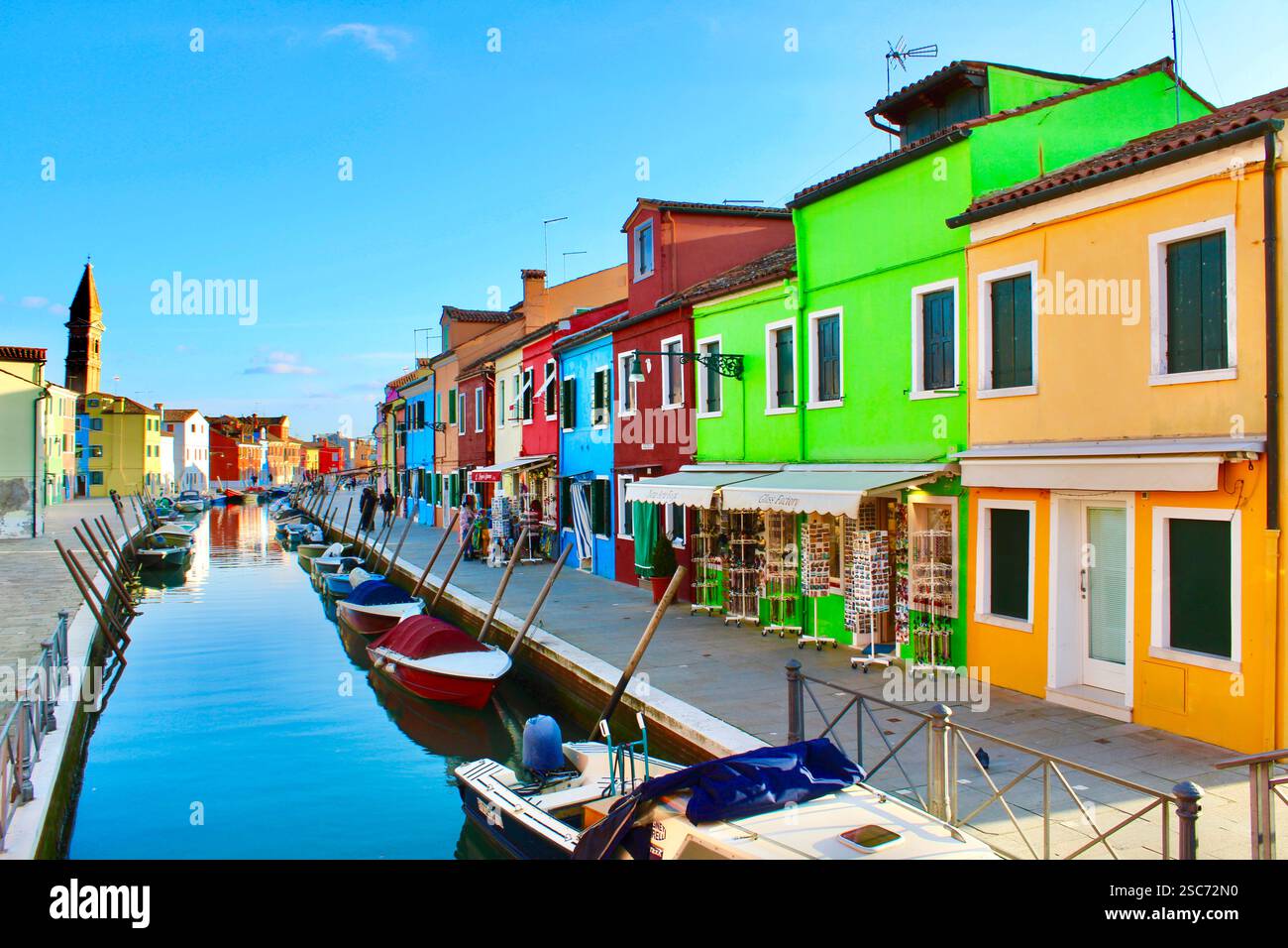 Colorful houses reflecting on the canal in Burano.A famous tourist destination known for its ...