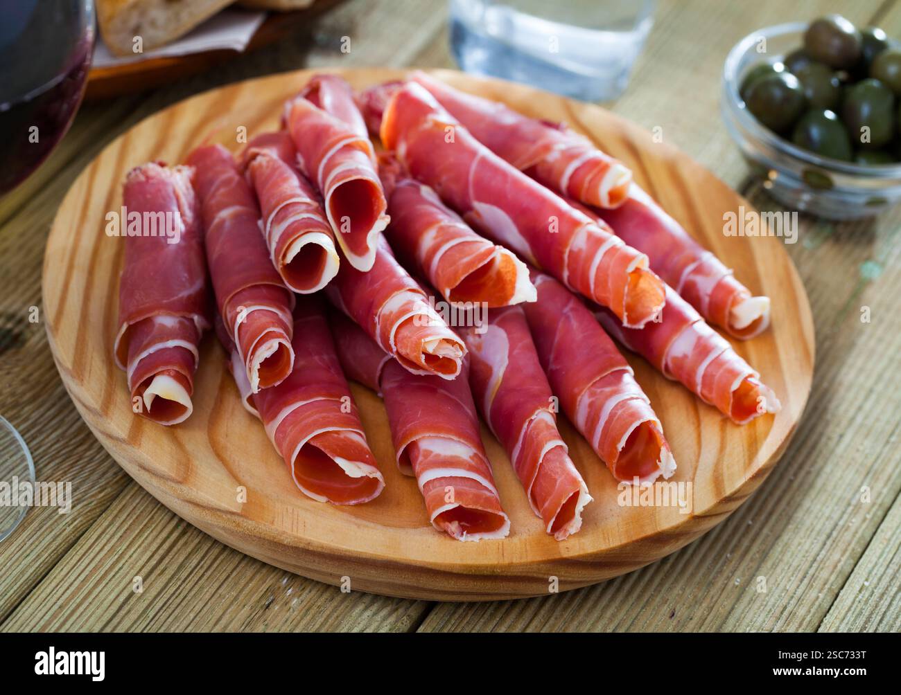 Spanish tapas - rolls of jamon serrano served on wooden board Stock Photo - Alamy