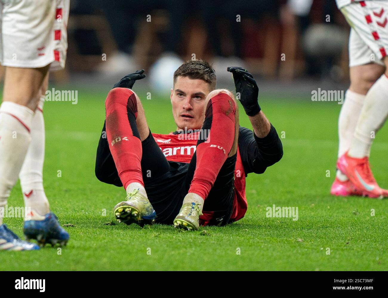 Patrik Schick (Bayer 04 Leverkusen, #14) sitzt enttäuscht auf dem Boden ...