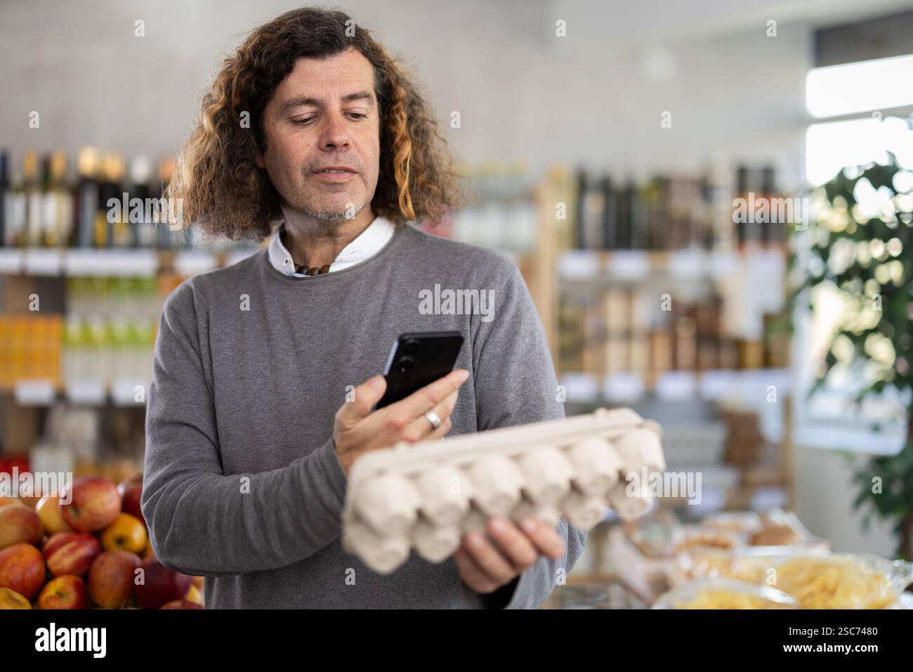 Male buyer scans QR code on packaging of chicken eggs label in grocery ...