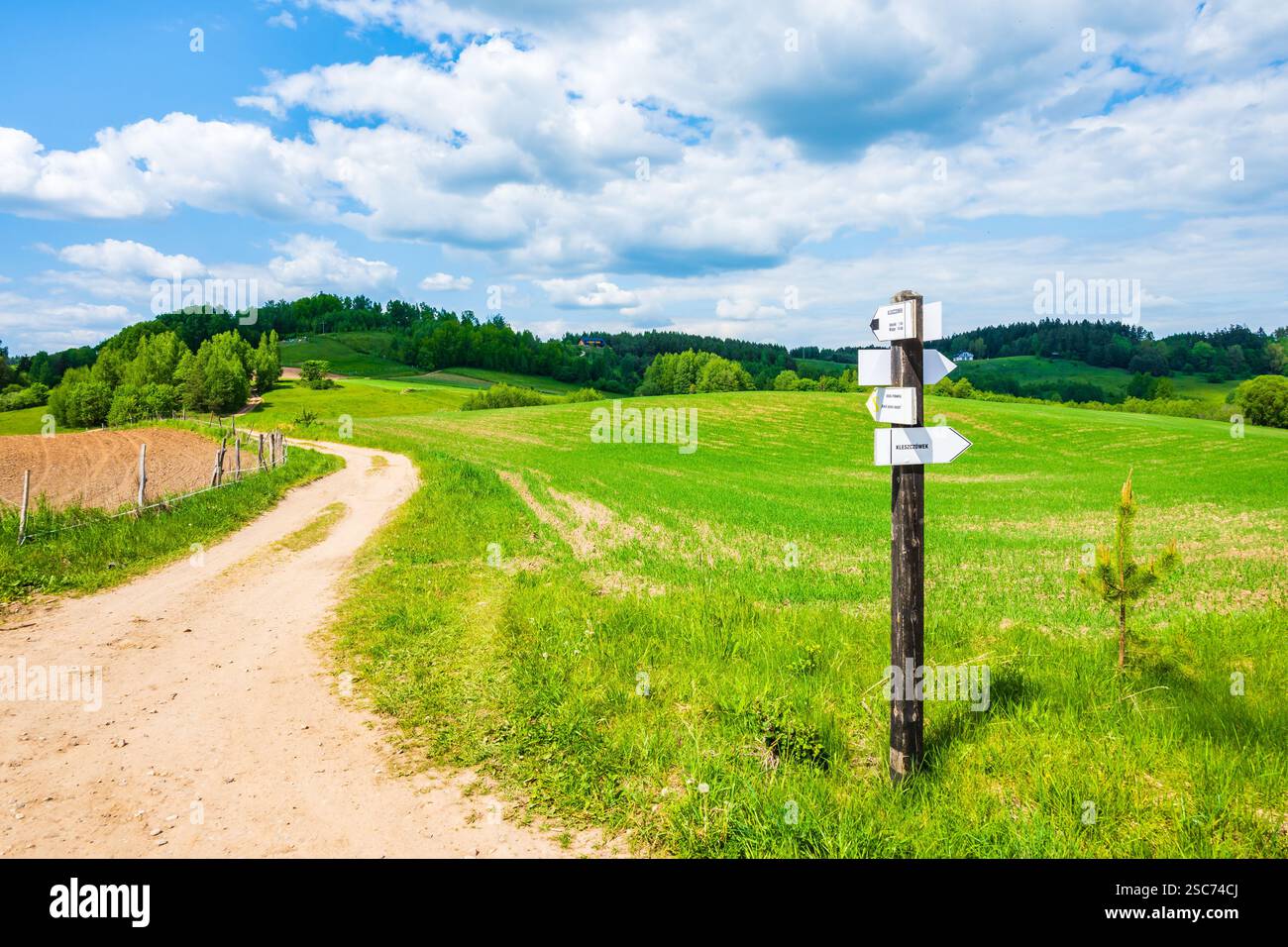 Post with cyclings routes signs on gravel road and green landscape ...