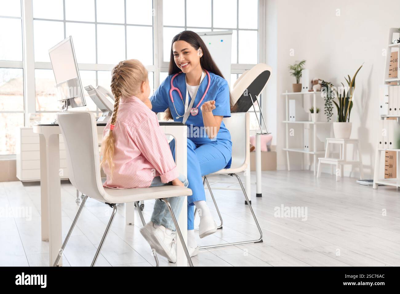 Female pediatrician working with little girl at table in clinic Stock ...