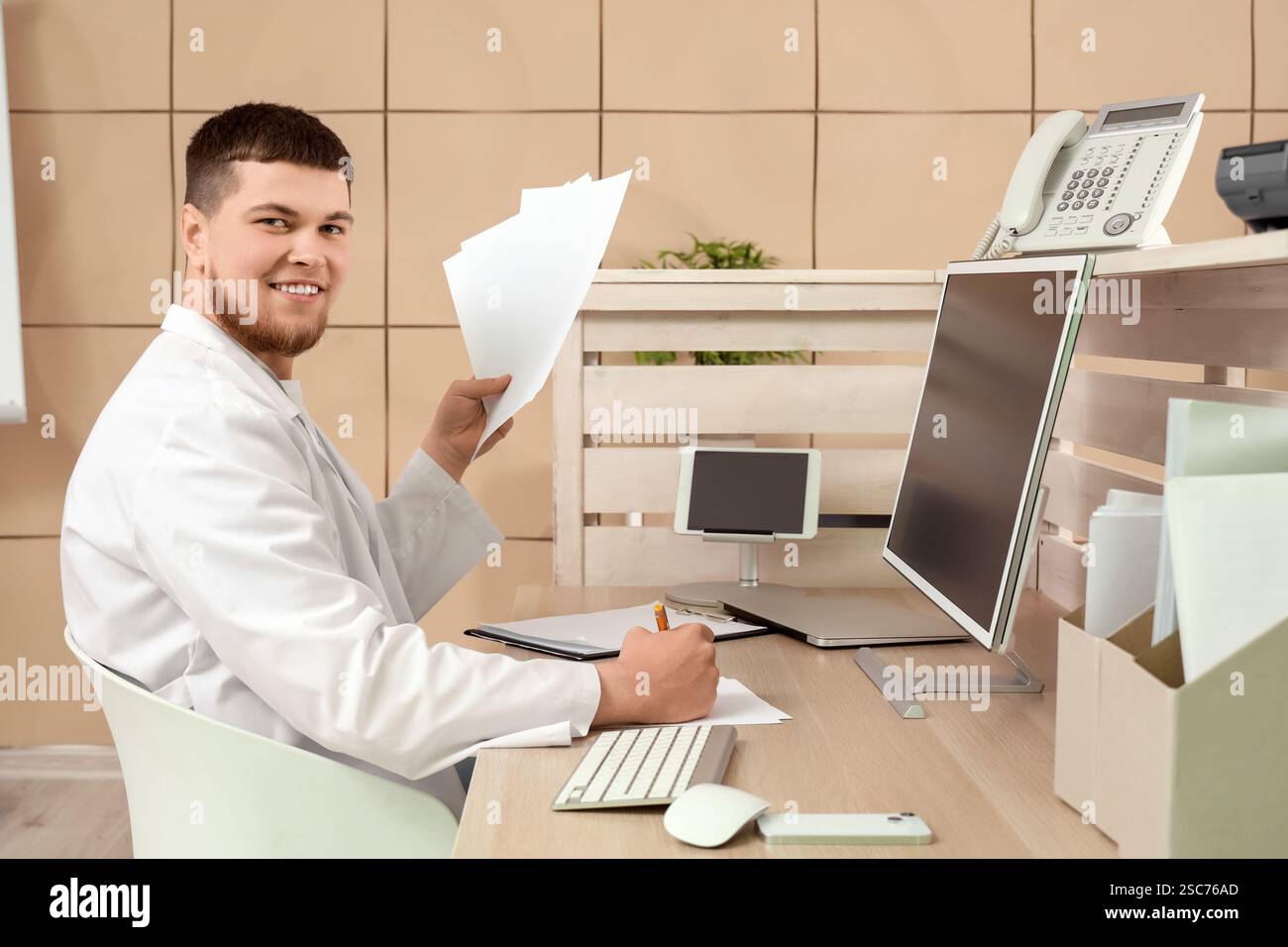 Male receptionist working with papers at hospital Stock Photo - Alamy