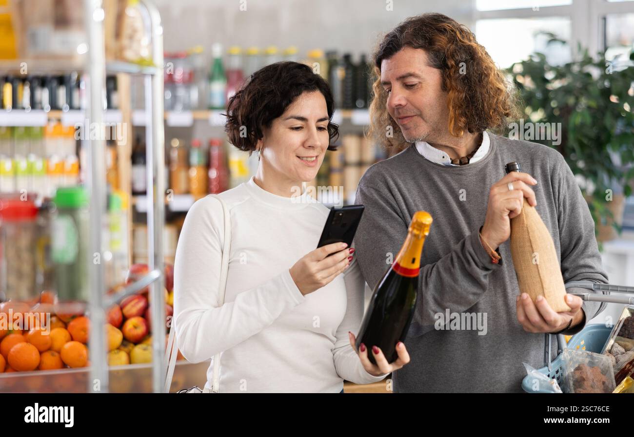 Checking expiration date of champagne - wife and husband shoppers scans ...