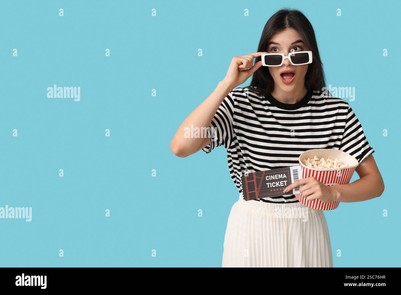 Young shocked woman in 3D cinema eyeglasses with popcorn bucket and ...