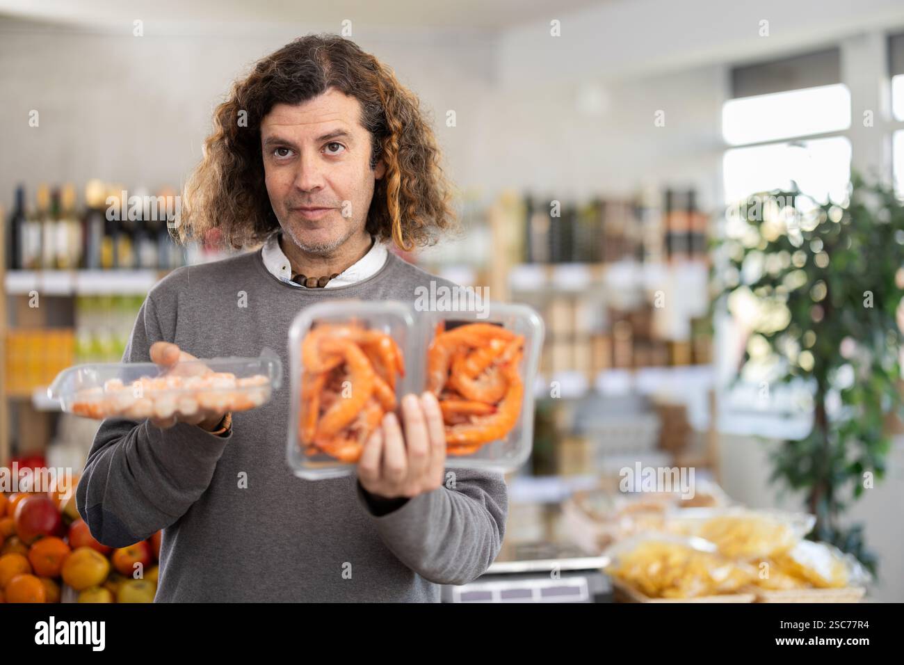 Adult man chooses prawns in grocery store Stock Photo - Alamy