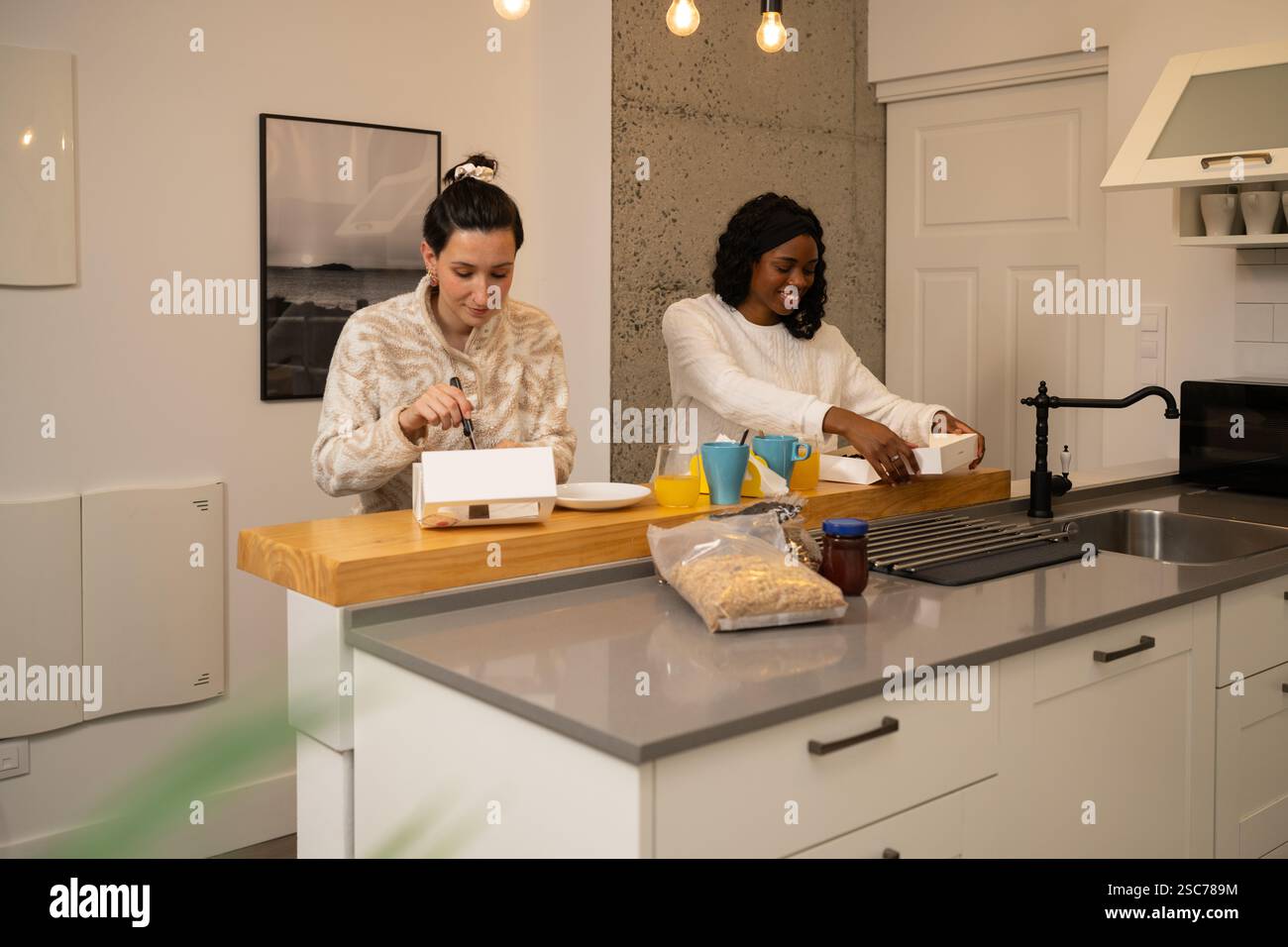 Two young women preparing breakfast in a modern kitchen, opening food ...