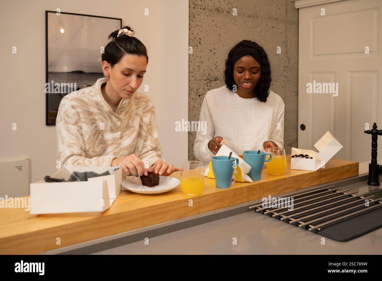 Two young women enjoying a cheerful breakfast moment in a modern ...
